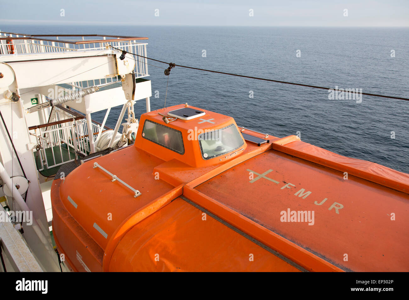An orange lifeboat attached to the side of a cross channel ferry with ...