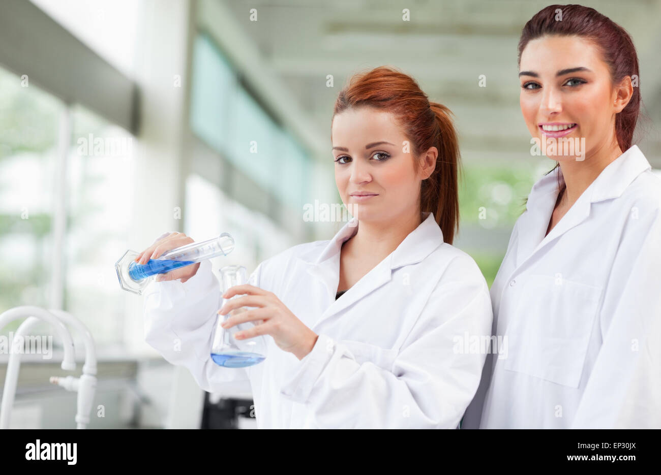 Scientists pouring blue liquid in an Erlenmeyer flask Stock Photo - Alamy