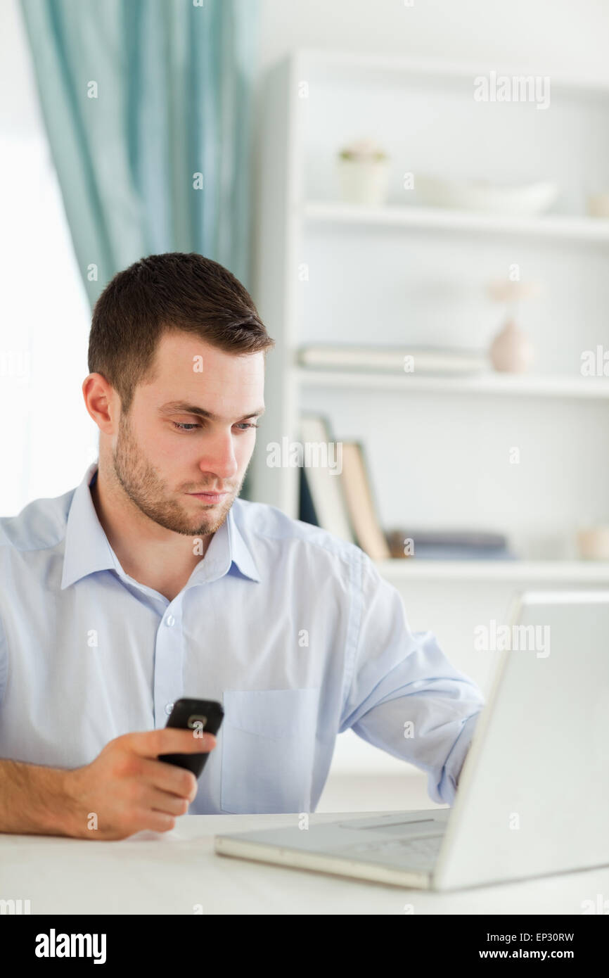 Businessman holding cellphone while typing Stock Photo - Alamy