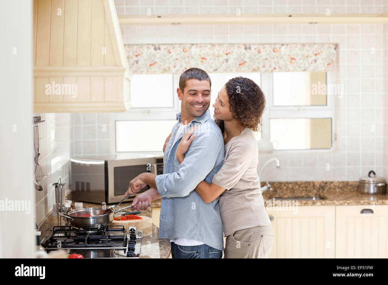 Woman hugging her husband while he is cooking Stock Photo - Alamy