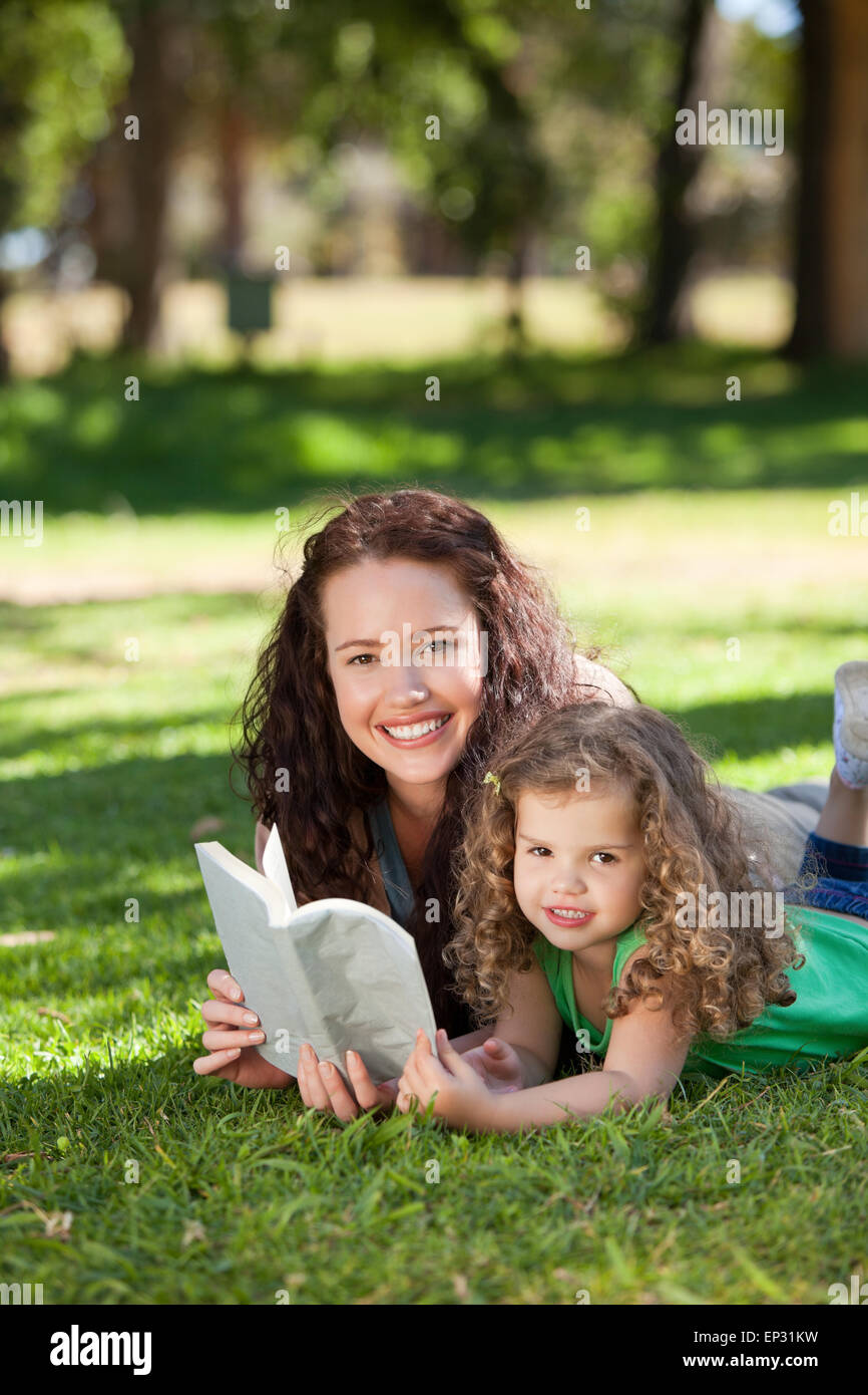 Woman with her daughter reading a book Stock Photo - Alamy