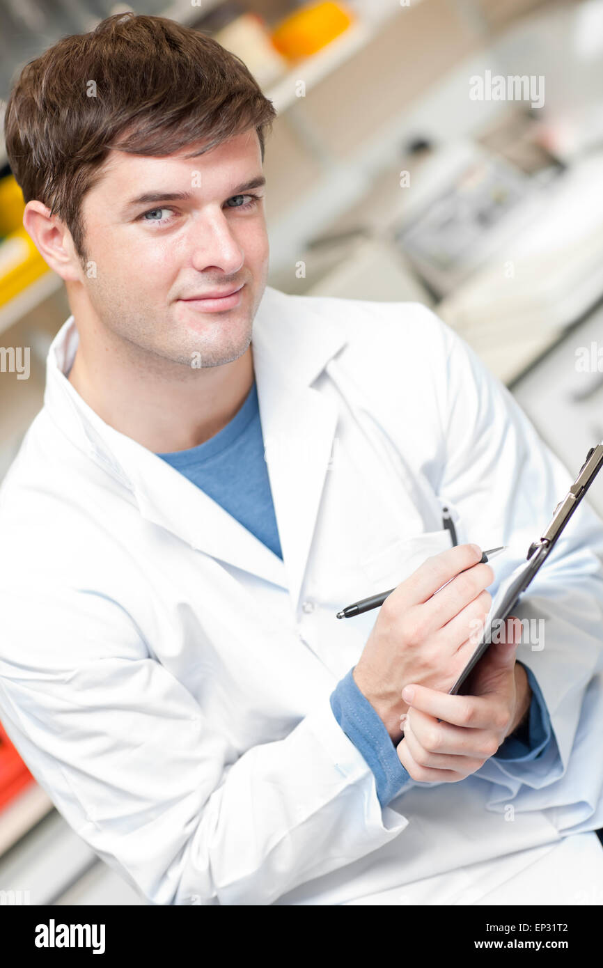 Handsome scientist holding a clipboard and smiling at the camera Stock ...