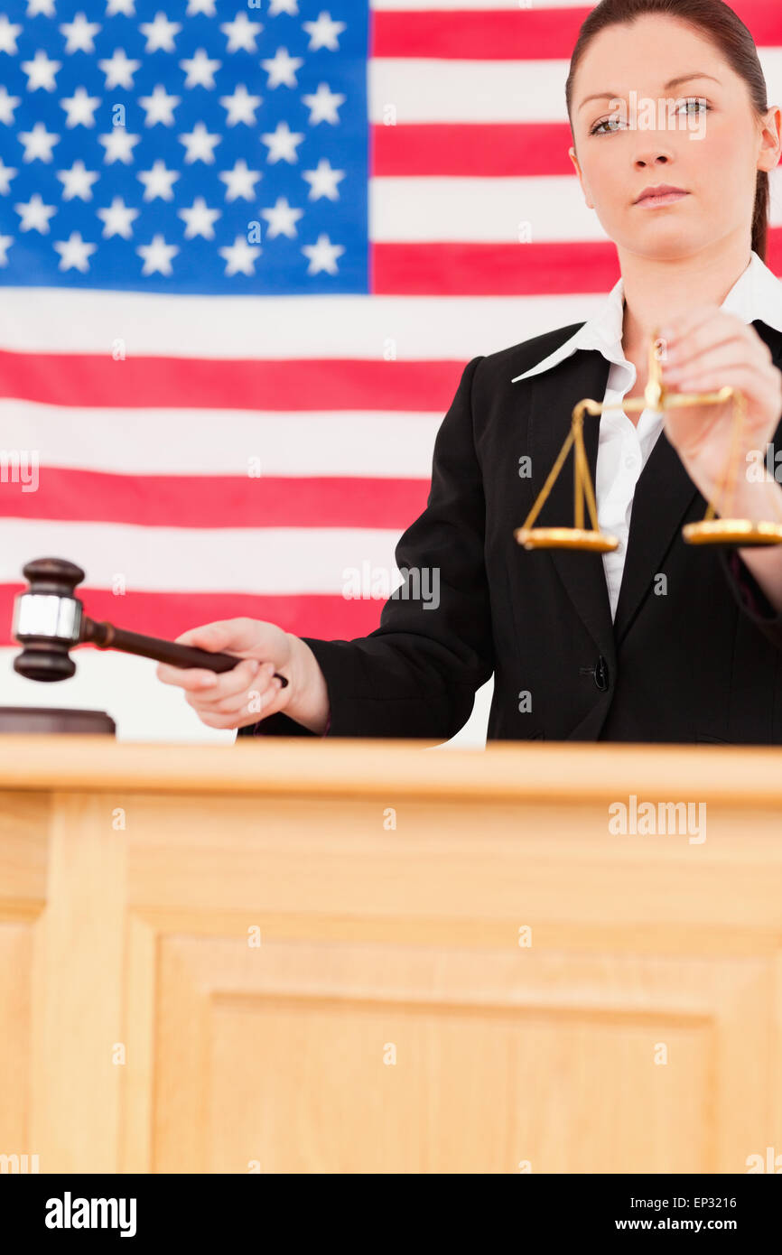 Portrait of a young judge knocking a gavel and holding scales of ...