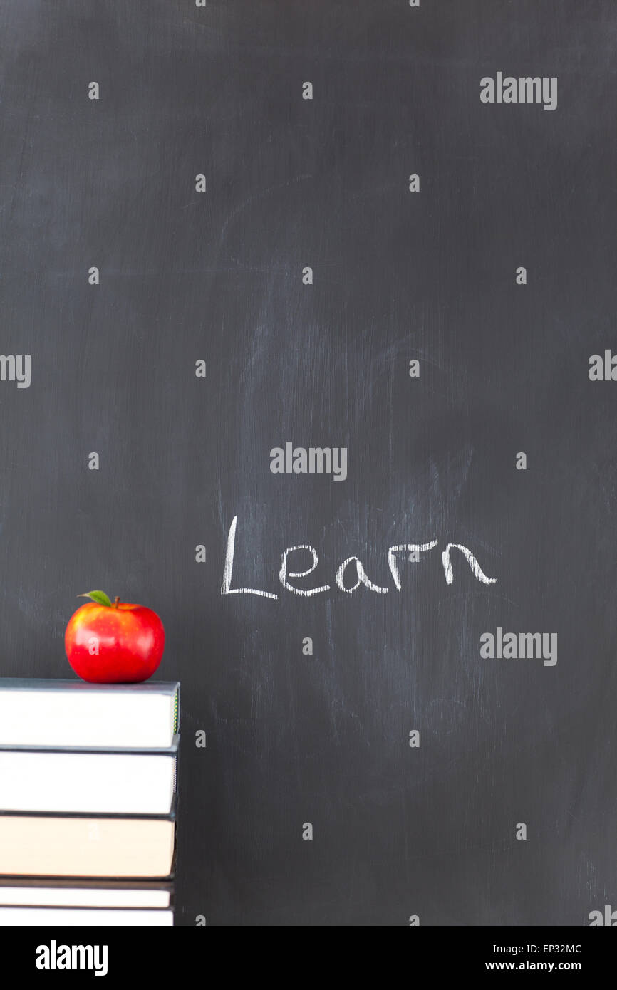 Stack of books with a red apple and a blackboard with learn written on ...