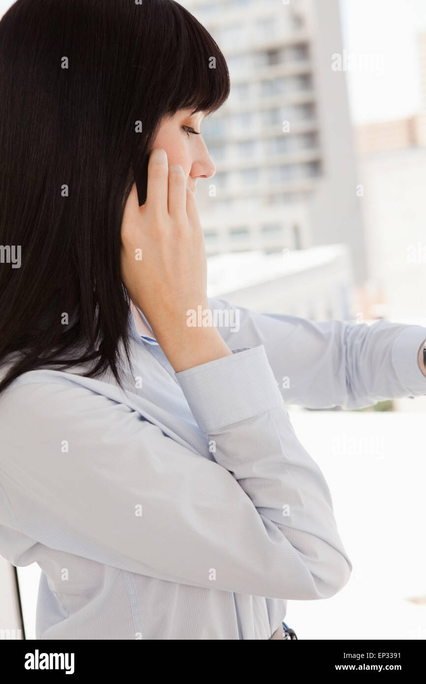 A woman looking at her watch as she calls someone Stock Photo - Alamy