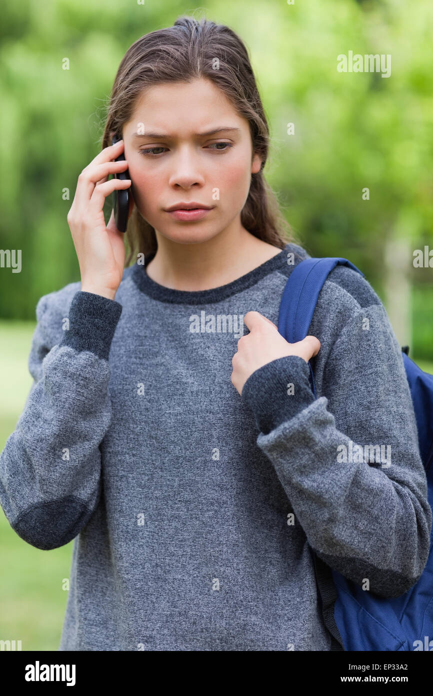 Serious student looking down while talking on the phone Stock Photo - Alamy