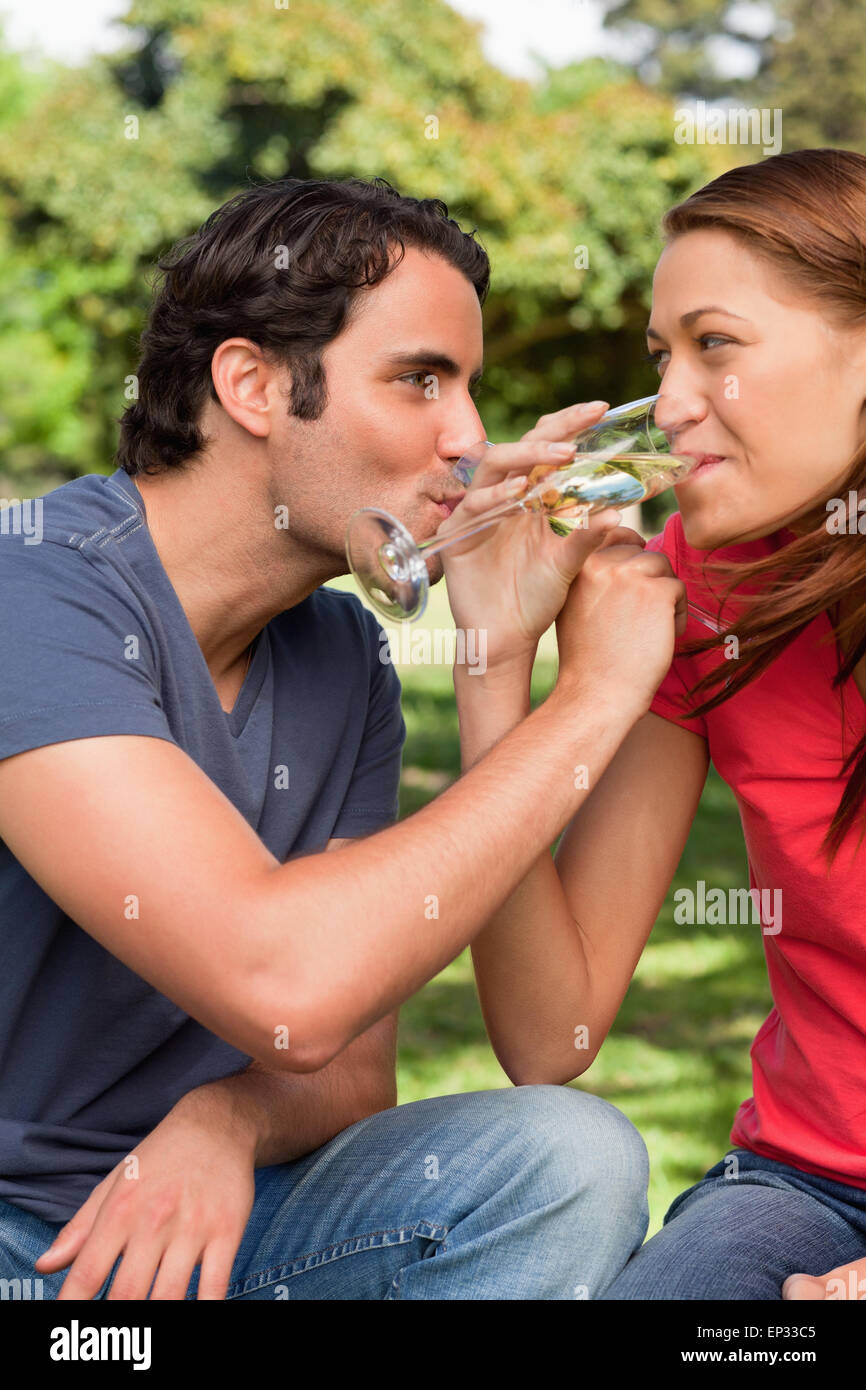 Two friends smiling as they link their arms together while drinking ...
