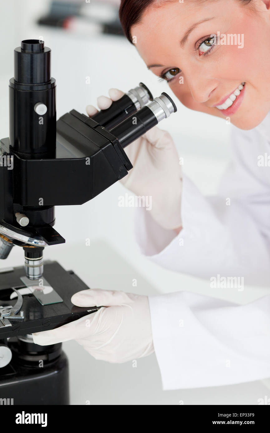 Charming red-haired scientist looking through a microscope Stock Photo ...
