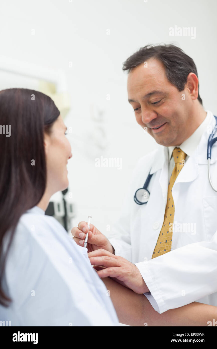 Smiling doctor doing an injection to a patient Stock Photo - Alamy
