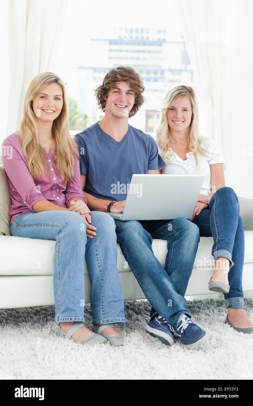 A group of friends sitting together as they use a laptop Stock Photo ...