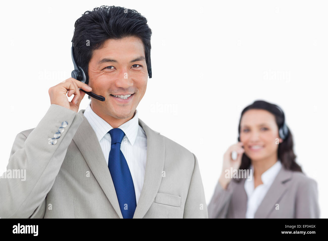 Smiling call center agent with colleague behind him Stock Photo - Alamy