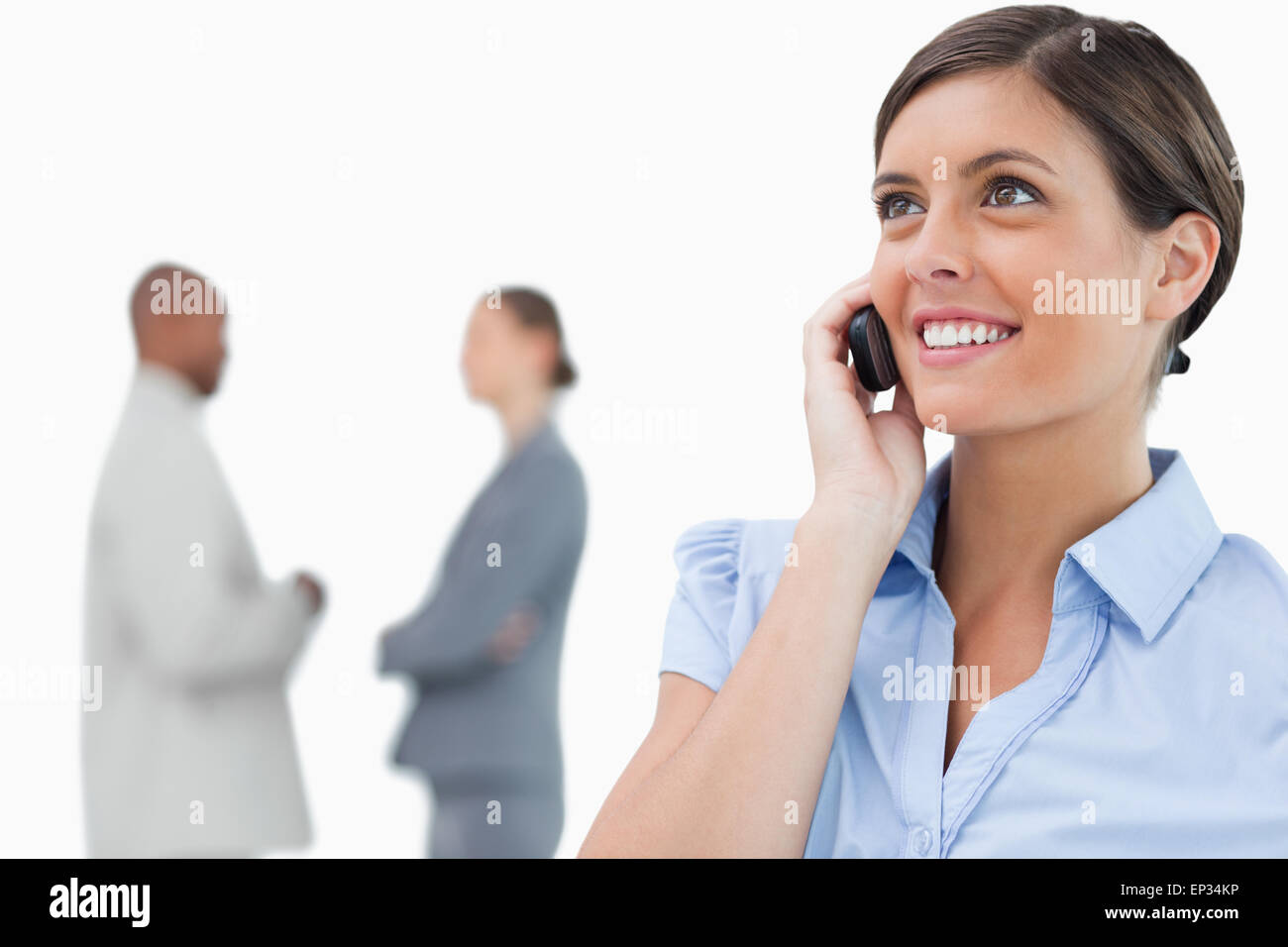 Smiling businesswoman with mobile phone and associates behind her Stock ...