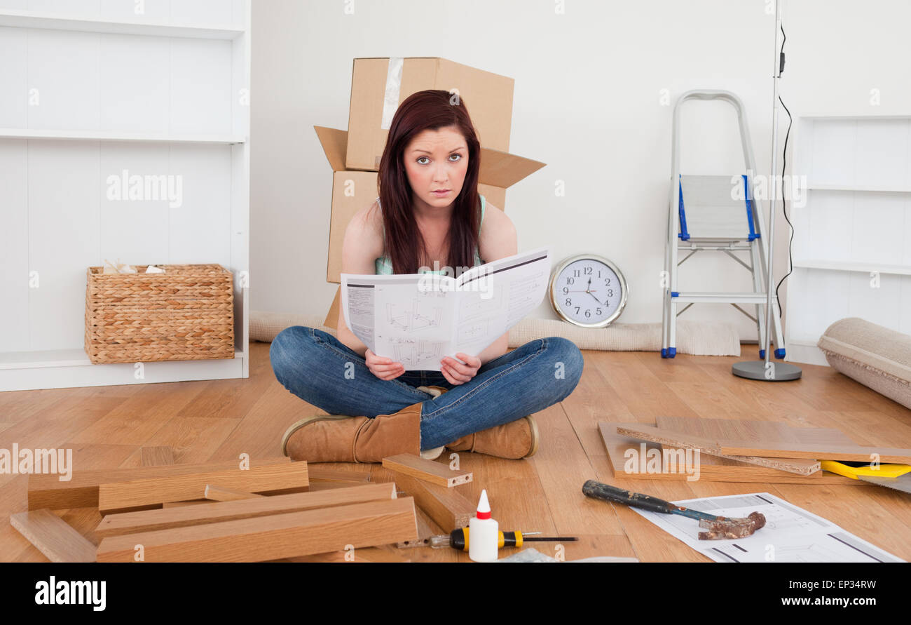 Attractive red-haired female reading a manual before do-it-yourself ...