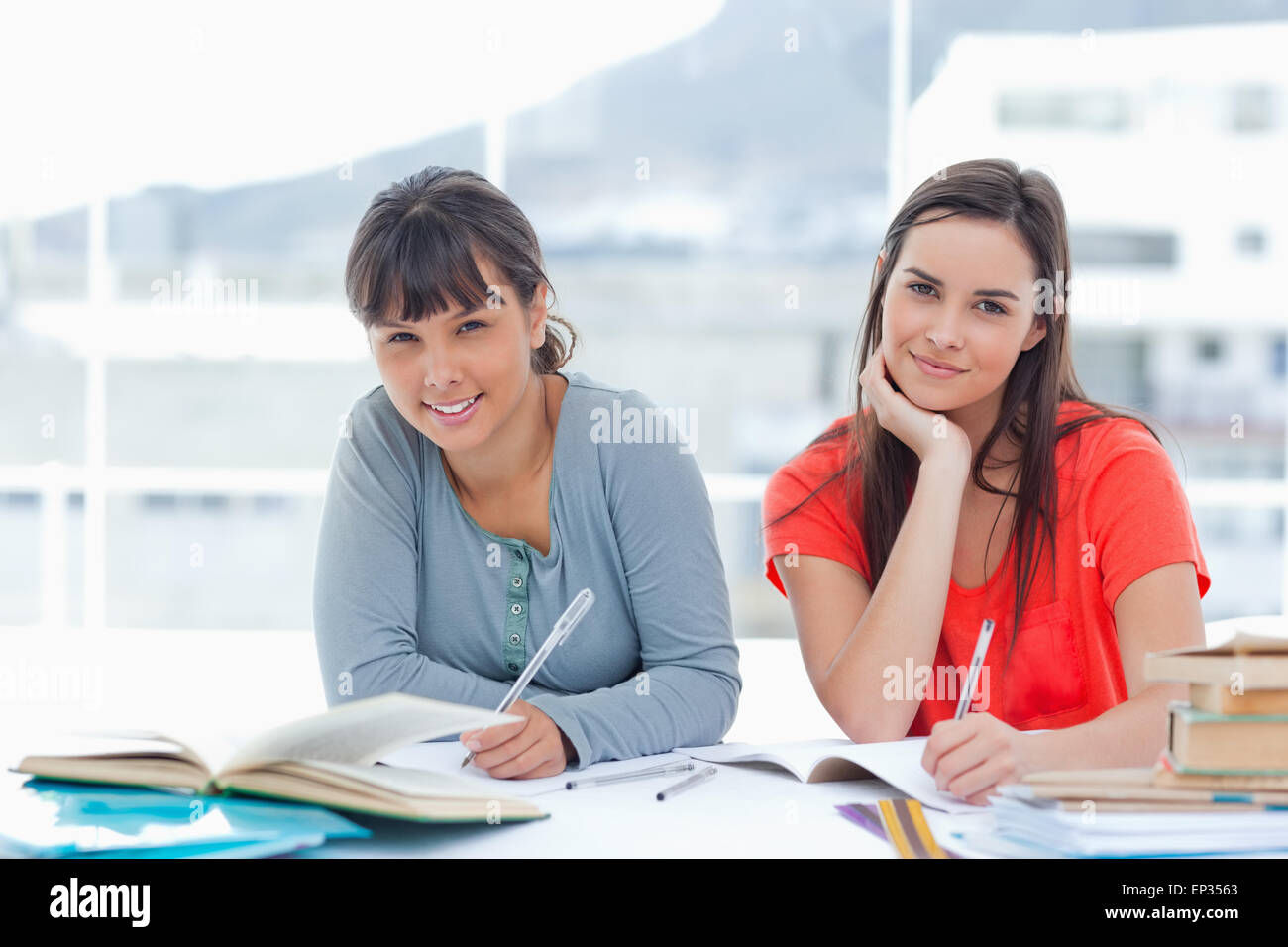 Two smiling students doing homework as they look into the camera Stock ...