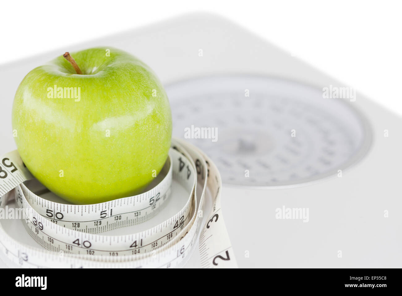 Closeup of a green apple circled with a tape measure and weigh-scale ...