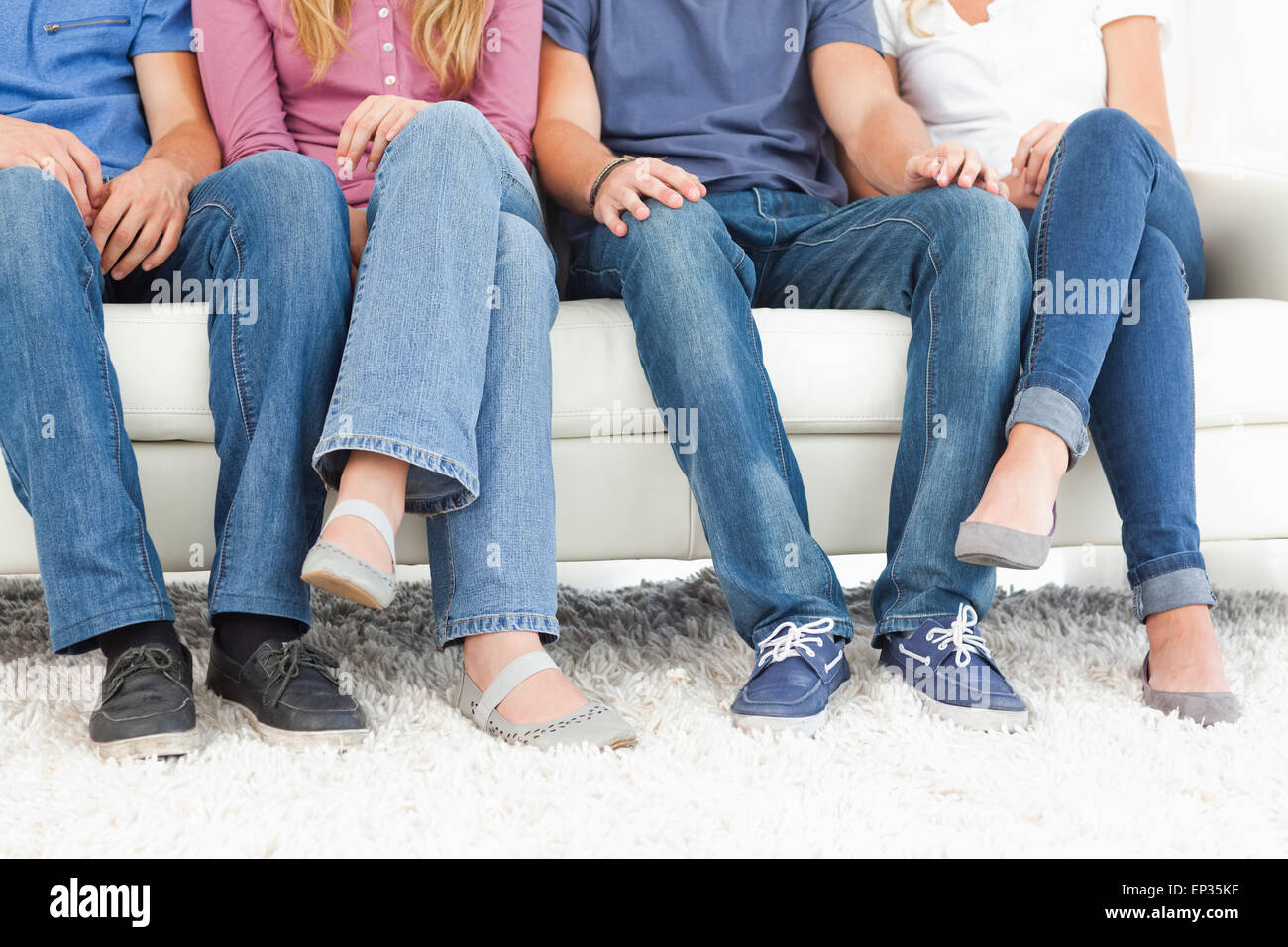 Four people sitting on the couch with the camera focused on the legs ...