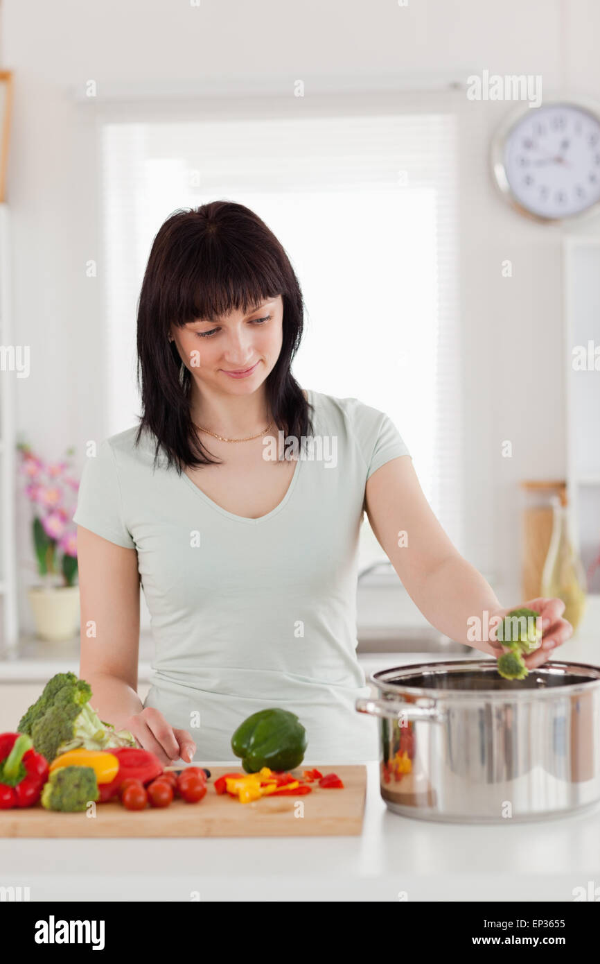 Beautiful brunette woman cooking vegetables Stock Photo - Alamy
