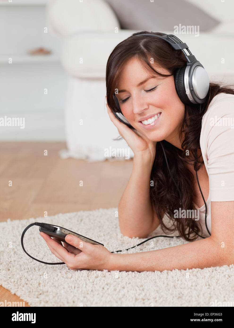 Good looking brunette female listening to music with her mp3 while ...