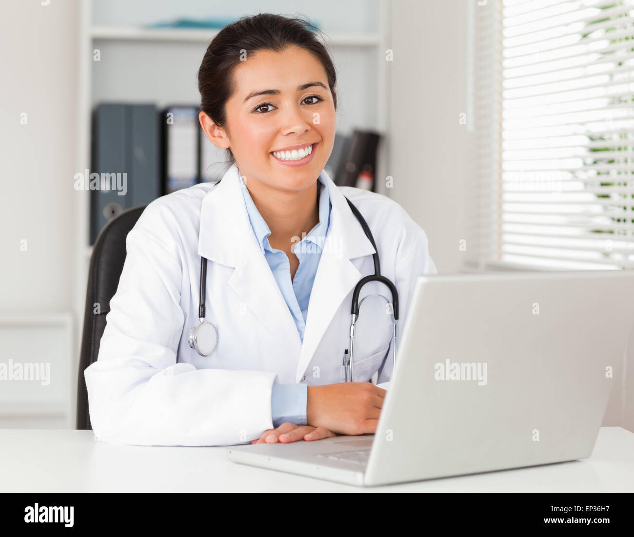 Good looking female doctor working with her laptop while posing Stock ...
