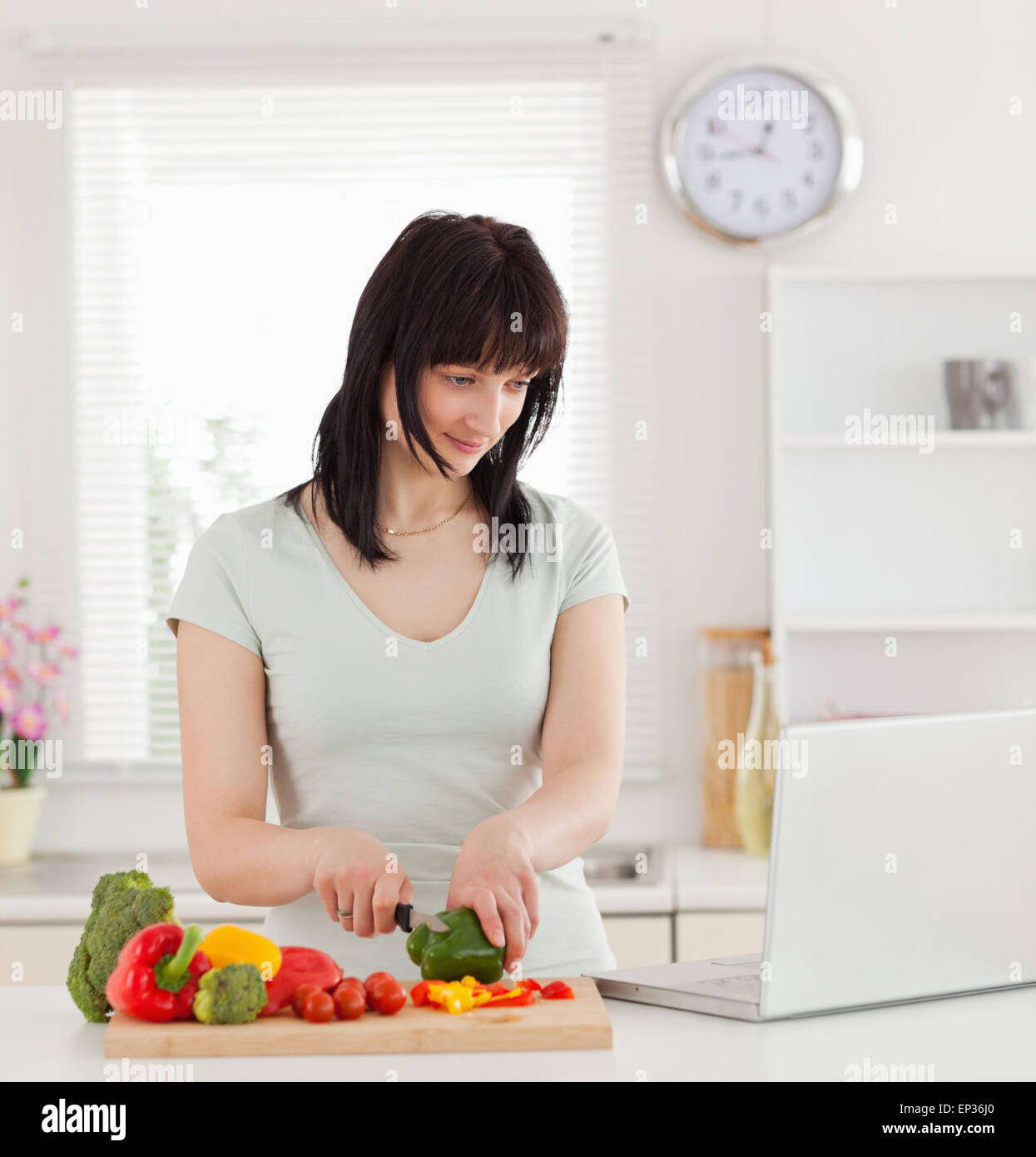 Beautiful brunette woman cooking while relaxing with her laptop Stock ...