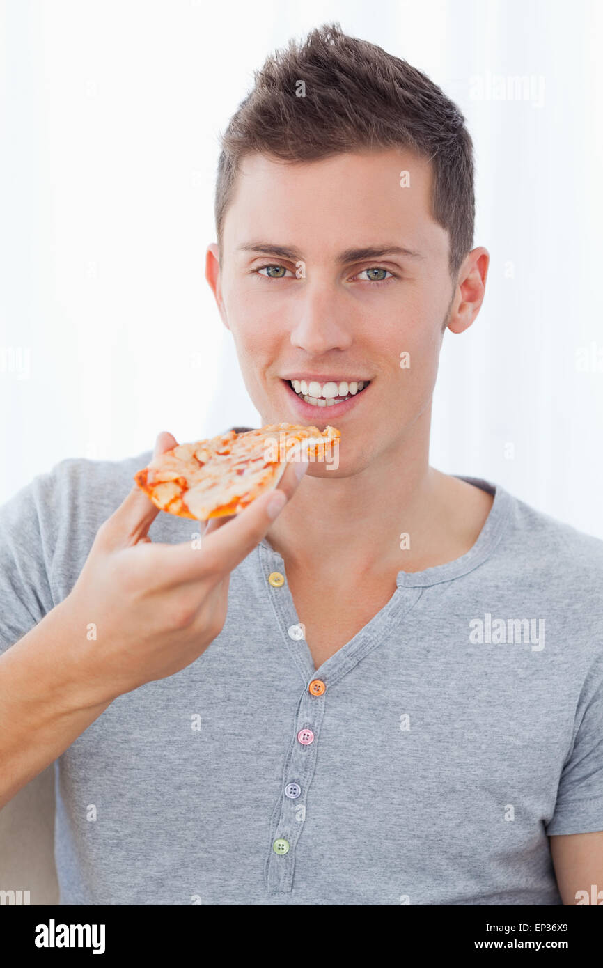 A smiling man holding pizza as he is about to eat Stock Photo - Alamy