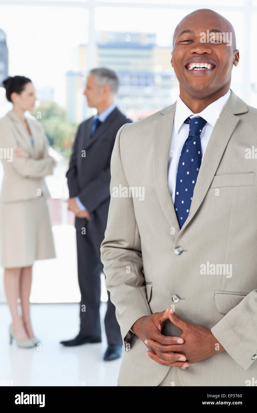 Young businessman laughing while standing upright with his hands ...