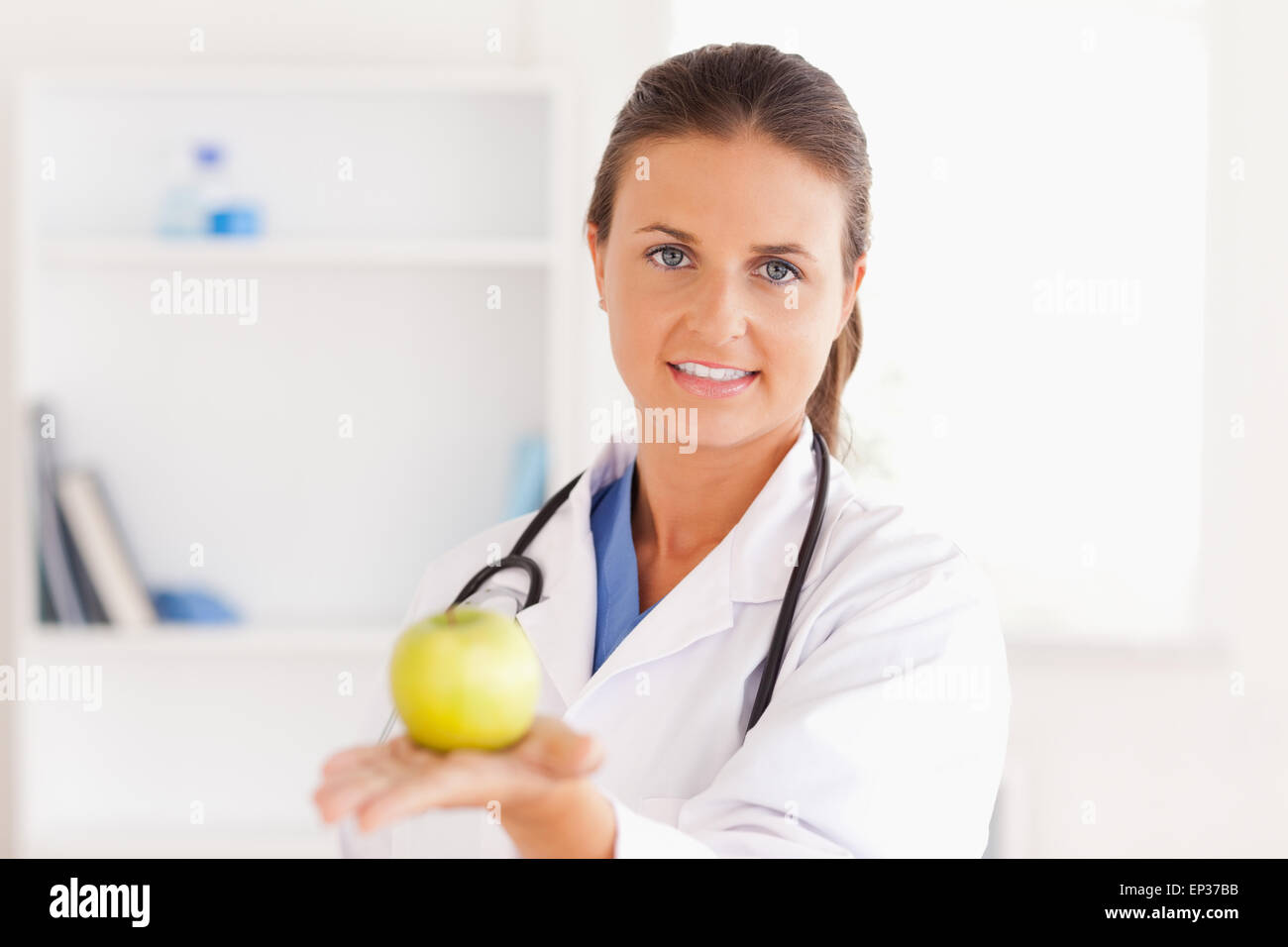 Doctor with stethoscope holding an apple looking into the camera Stock ...