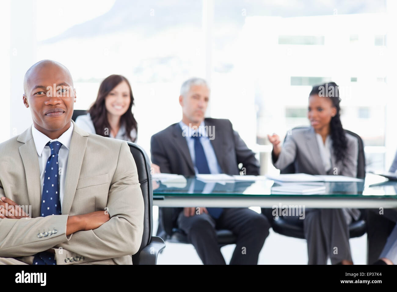 Young businessman almost smiling in front of his team who are sitting ...