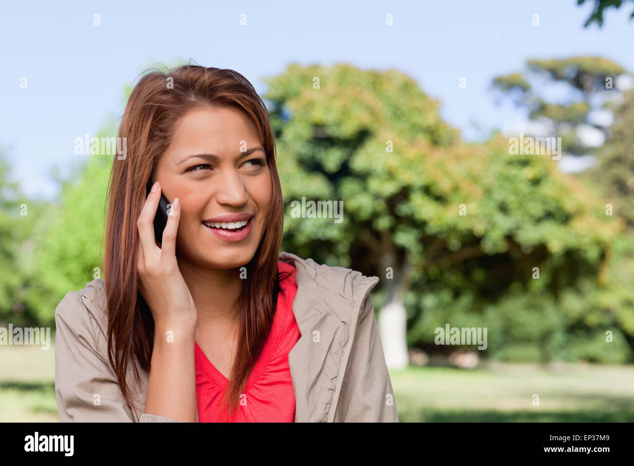 Woman smiling while looking towards her left side in an open grassland ...