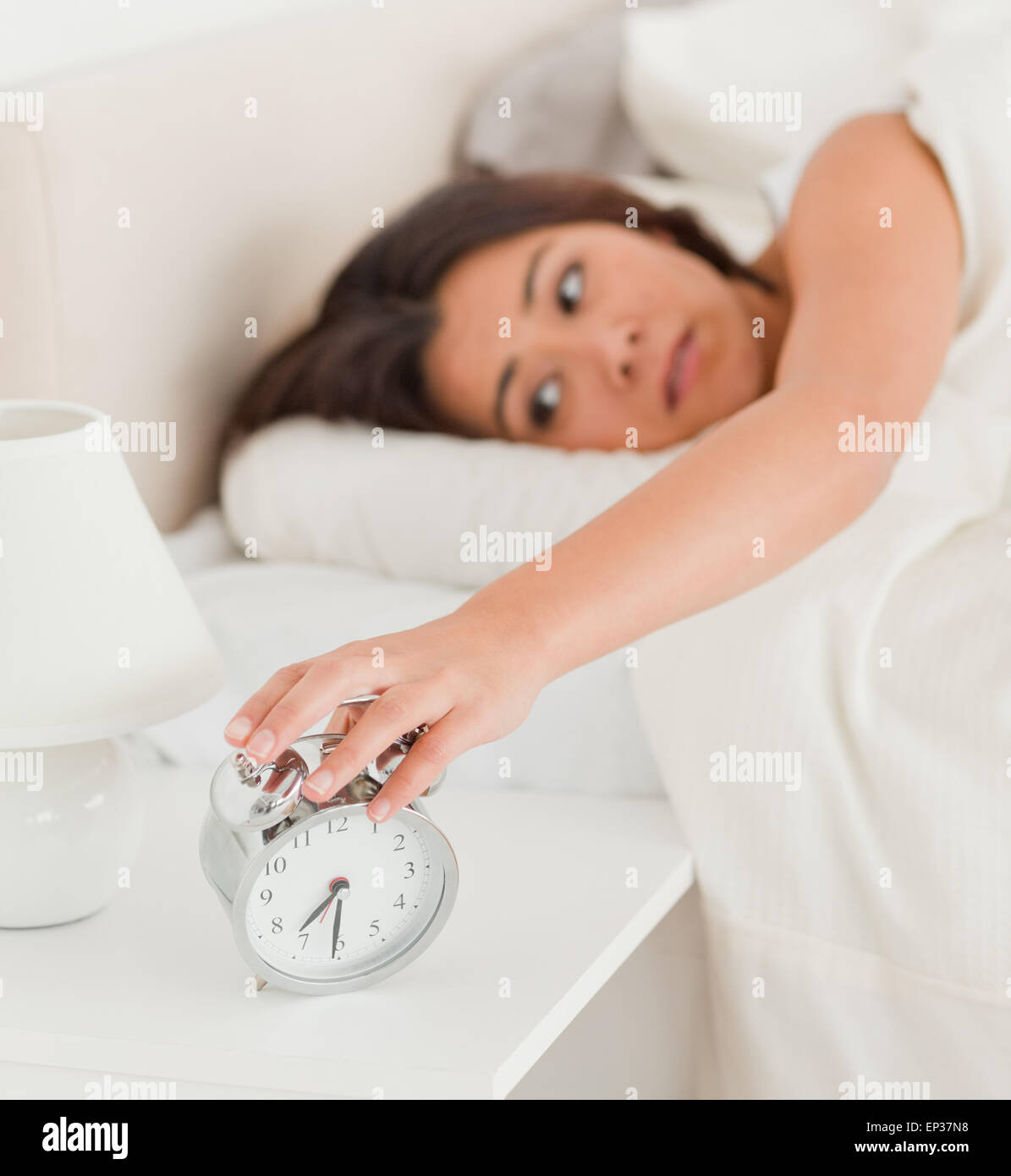 charming woman waking under sheet turning off alarm clock Stock Photo ...