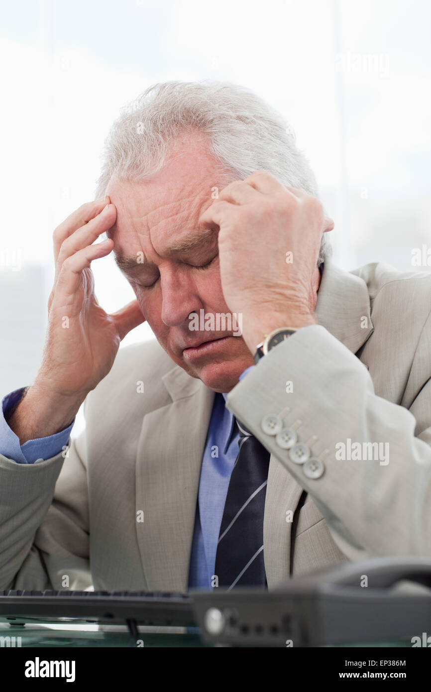 Portrait of an exhausted senior manager having a headache Stock Photo ...