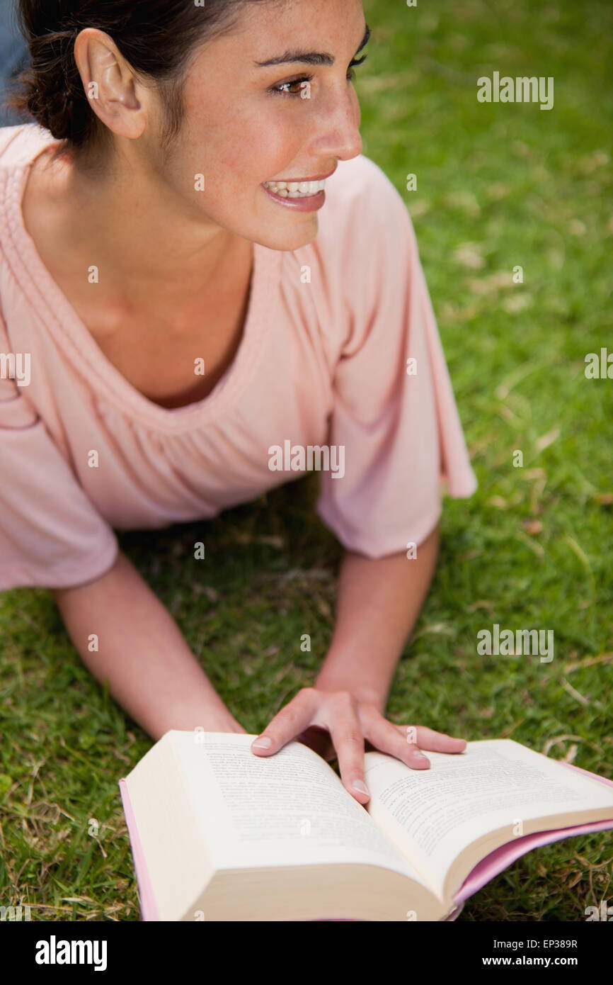 Woman looks to the side while reading a book as she is lying down Stock ...