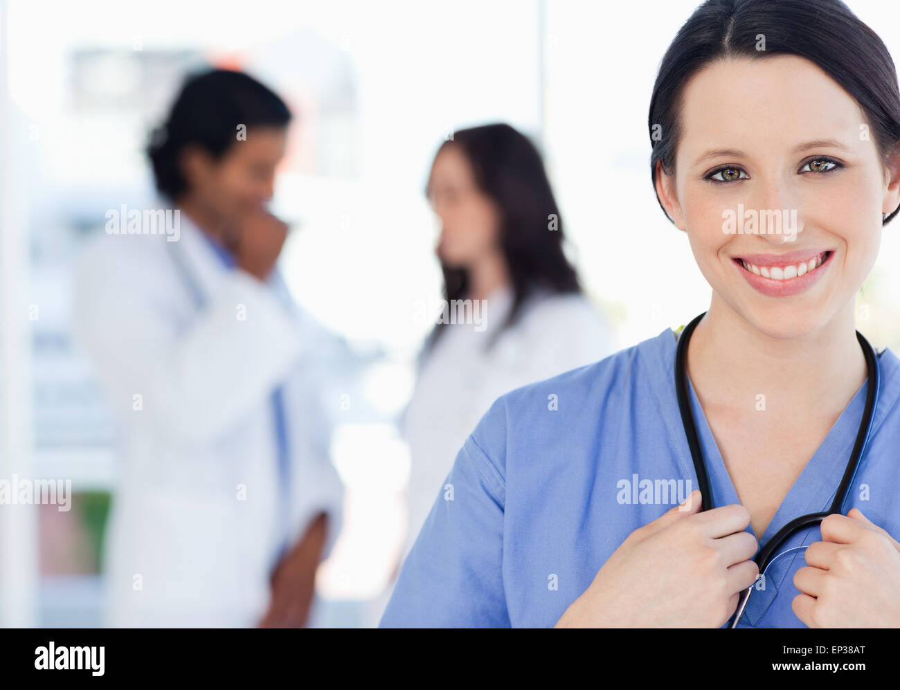 Confident nurse standing upright accompanied by her team in the ...