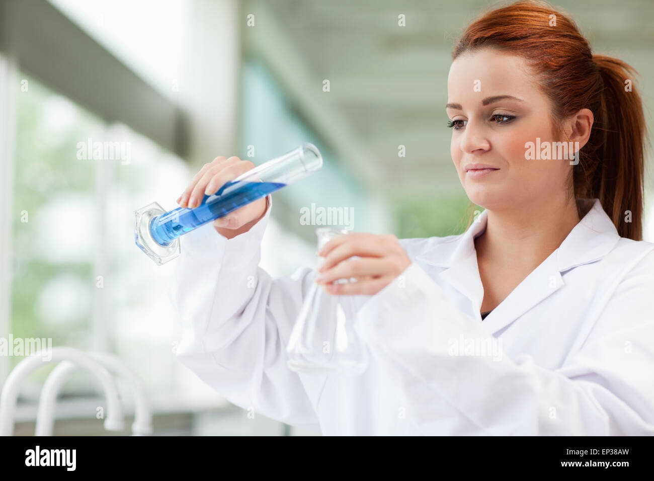 Scientist pouring liquid in an Erlenmeyer flask Stock Photo - Alamy