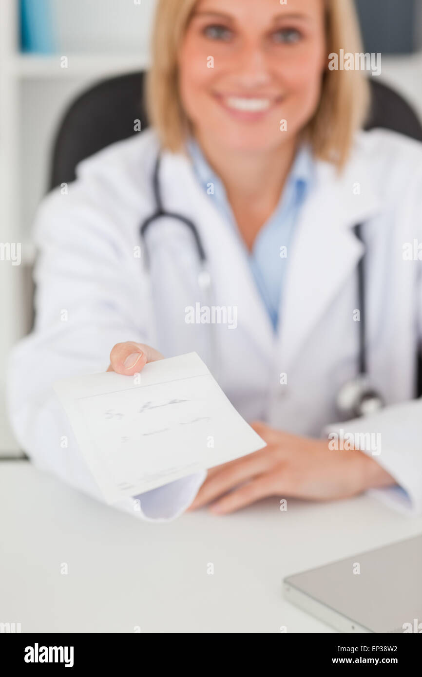 Smiling blonde doctor giving prescription looks into camera Stock Photo ...