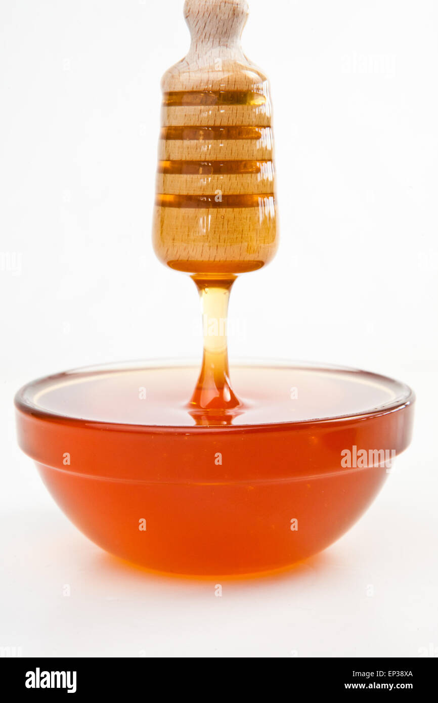 Thin honey trickle dropping in full honey bowl Stock Photo - Alamy