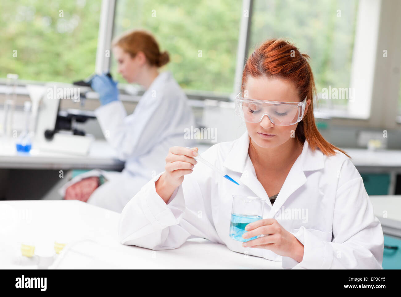 Scientist dropping blue liquid in a beaker Stock Photo - Alamy