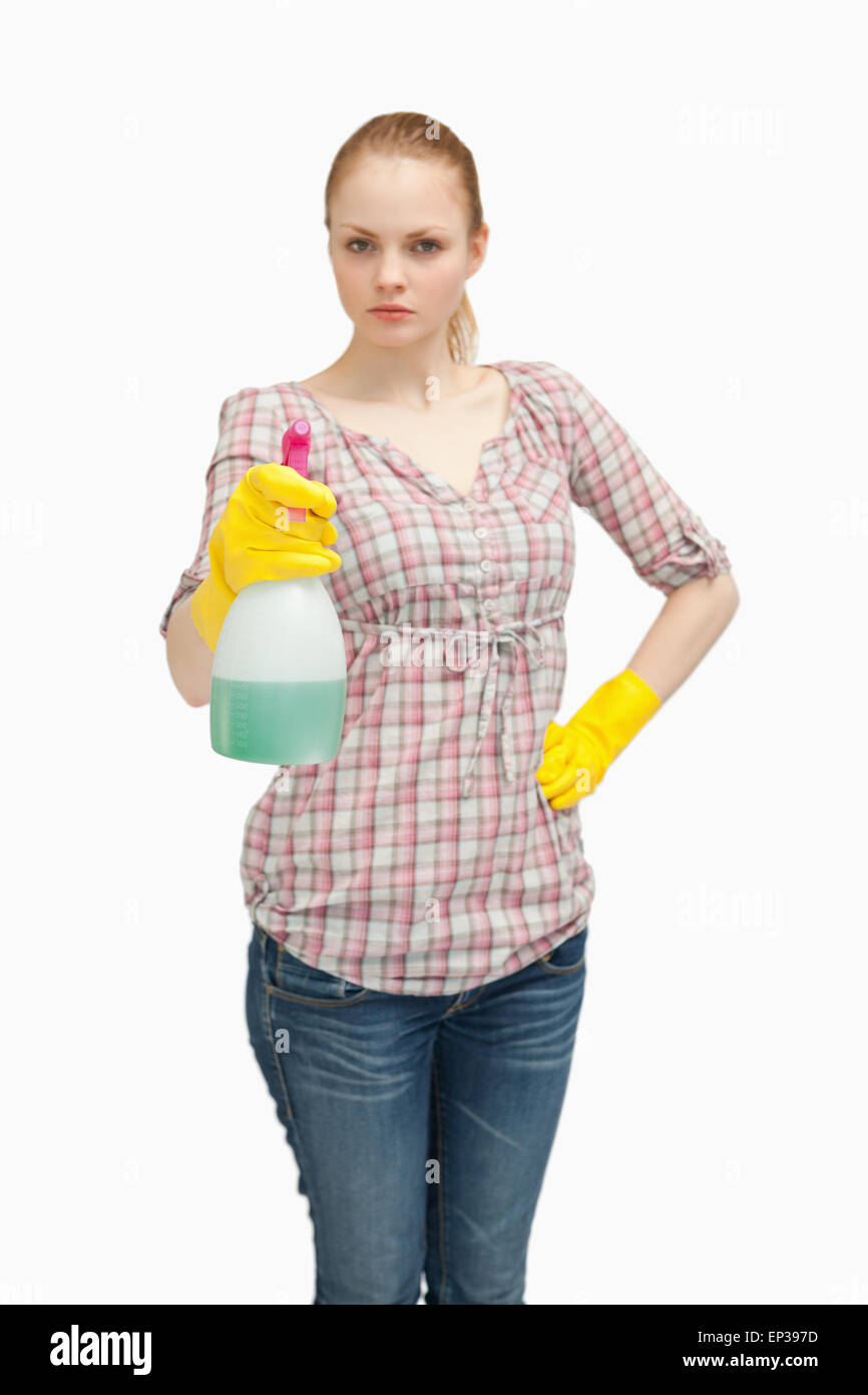 Serious woman holding a spray bottle while standing Stock Photo - Alamy