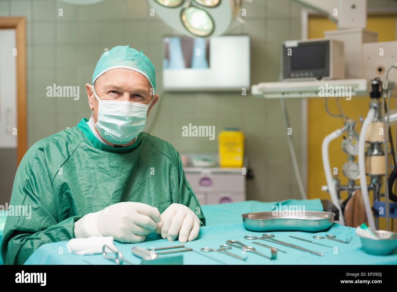 Surgeon sitting next to a table full of a surgical tools Stock Photo ...