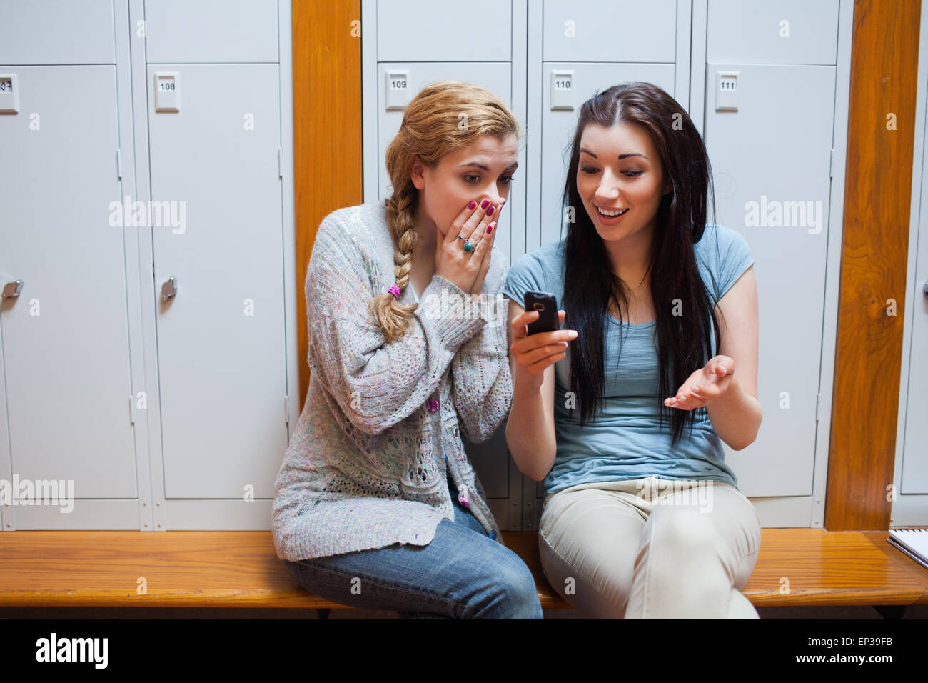 Surprised student showing a text message to her friend Stock Photo - Alamy