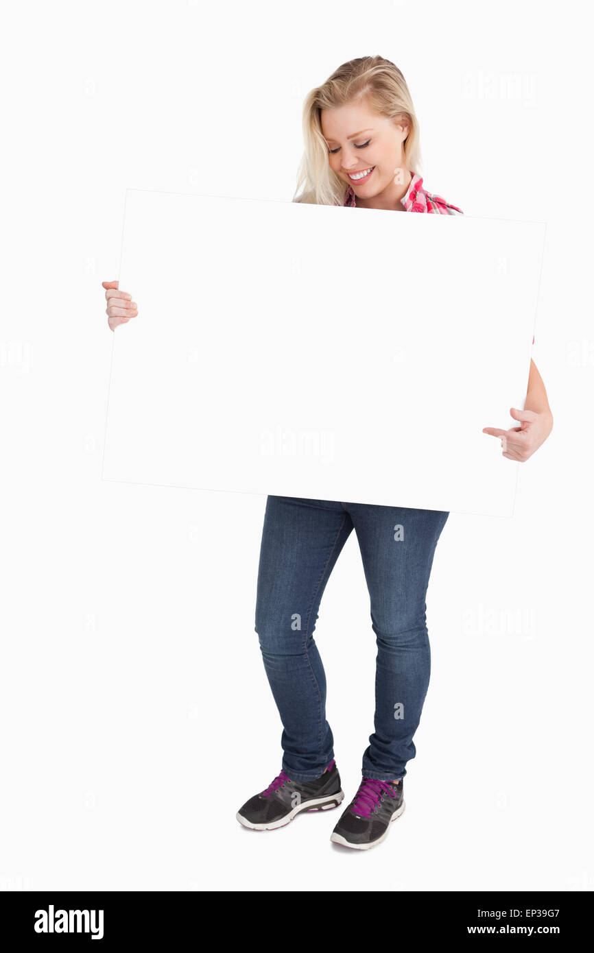 Smiling blonde woman pointing at a blank sign Stock Photo - Alamy