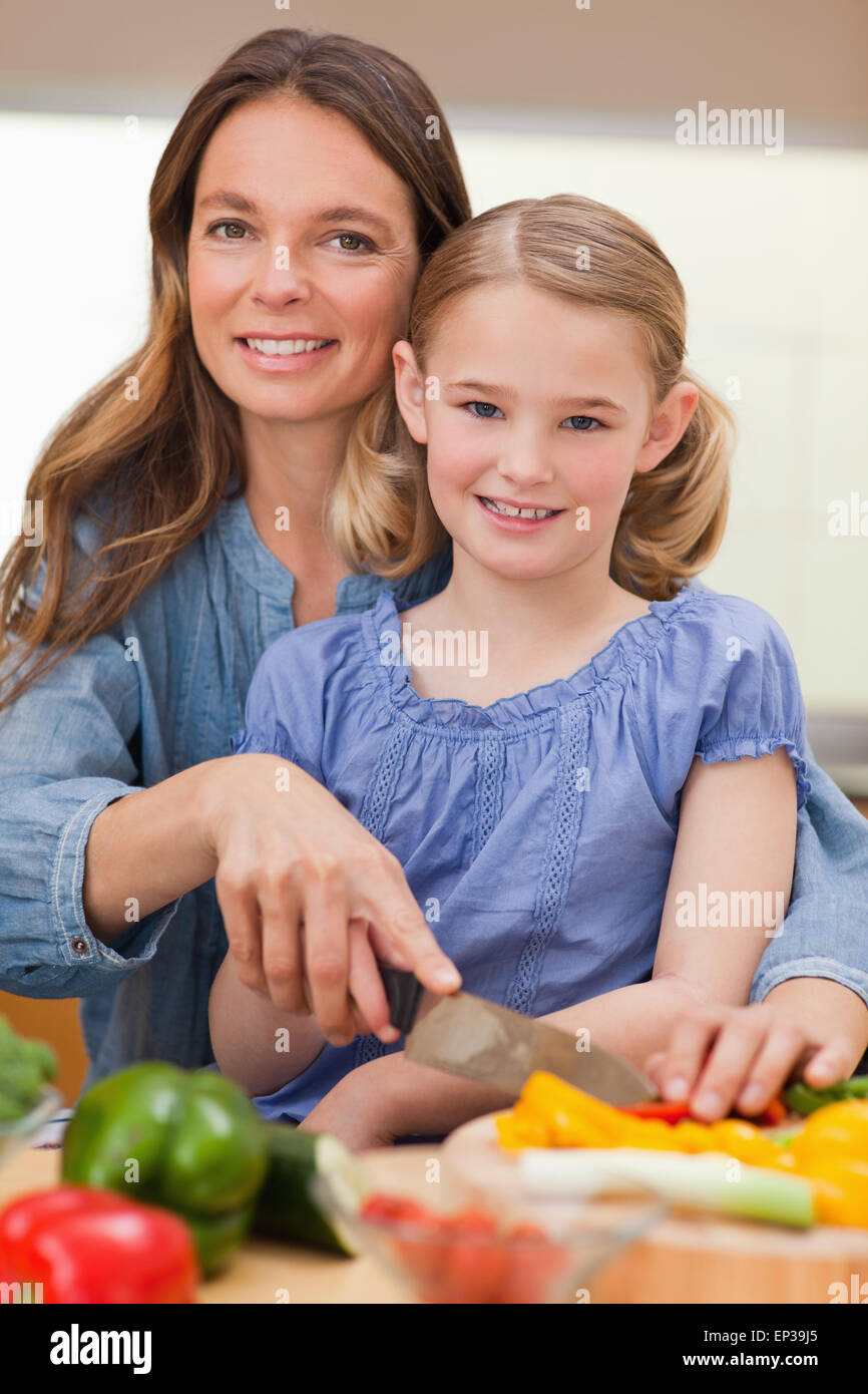 Portrait of a woman slicing bell pepper with her daughter Stock Photo ...