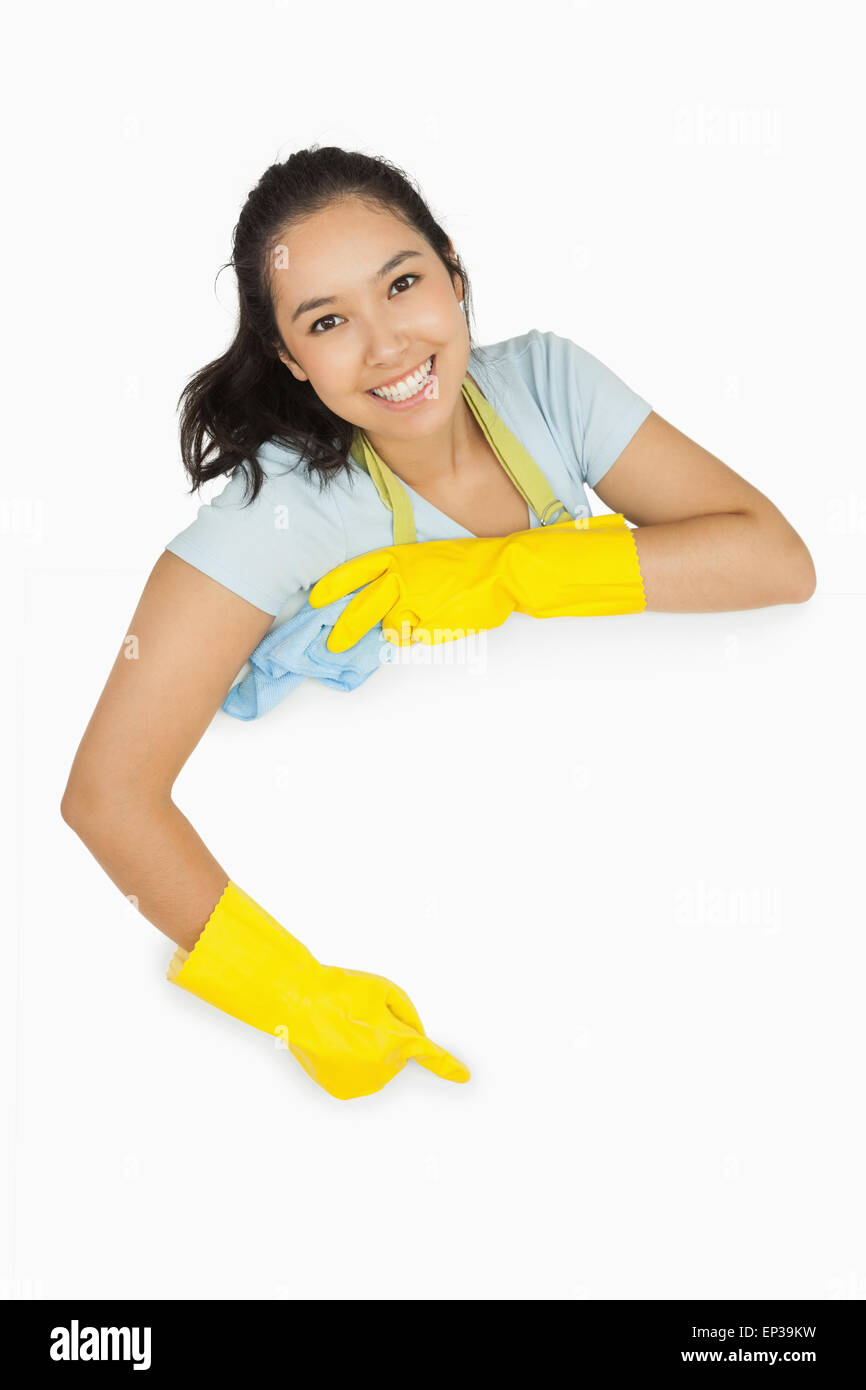 Happy cleaning lady pointing to white surface Stock Photo - Alamy