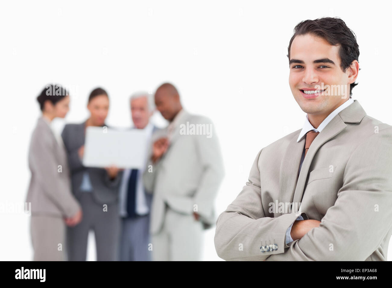 Smiling salesman with arms folded and colleagues behind him Stock Photo ...