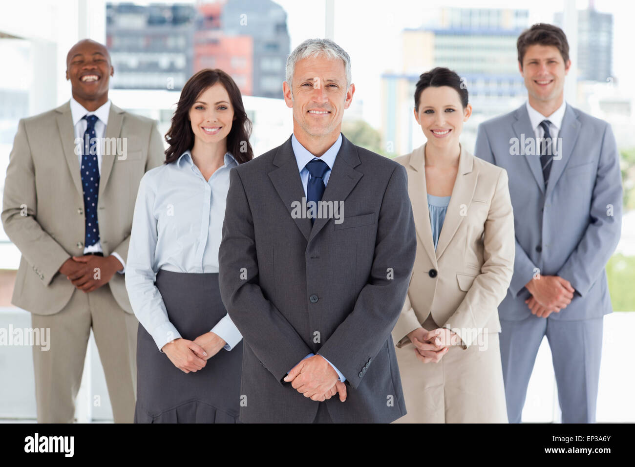 Mature smiling manager standing upright and followed by his team Stock ...
