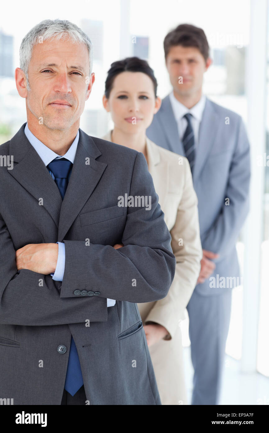 Serious manager crossing his arms in front of his business team Stock ...