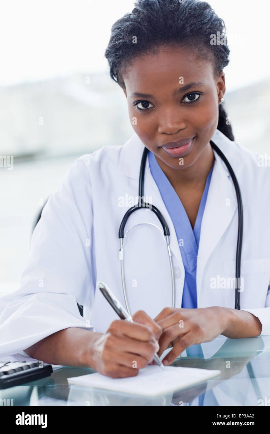 Portrait of a young female doctor writing a prescription Stock Photo ...