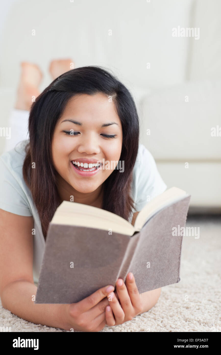 Smiling woman reading a book as she sits on the floor Stock Photo - Alamy