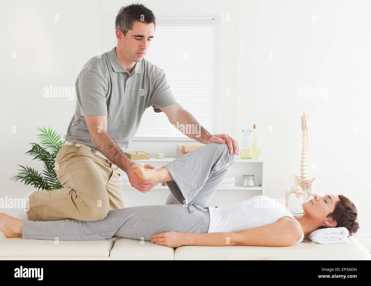 Chiropractor stretching young woman's leg Stock Photo - Alamy
