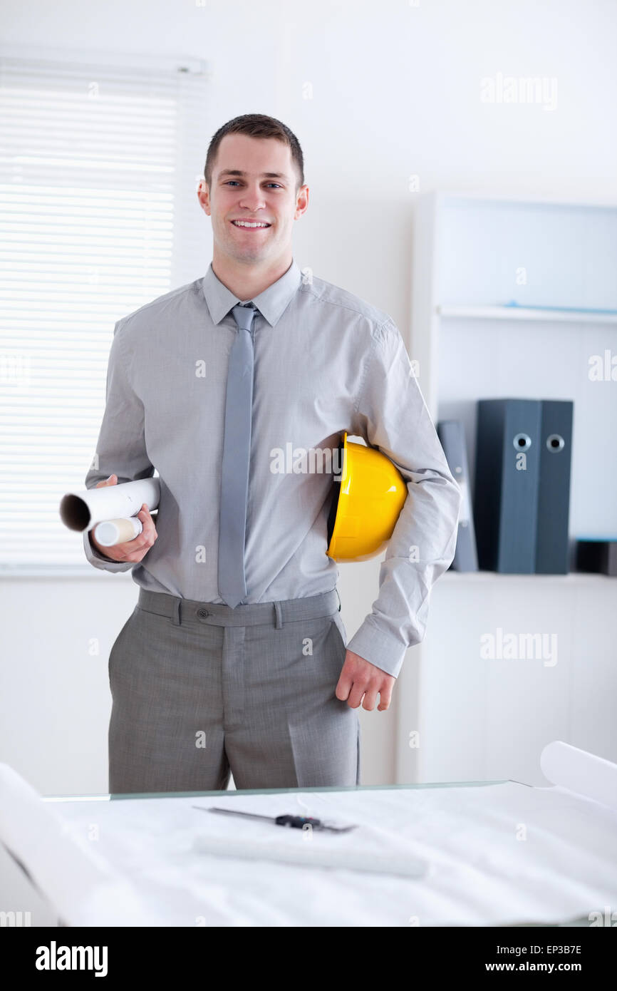 Architect carrying plans and helm Stock Photo - Alamy